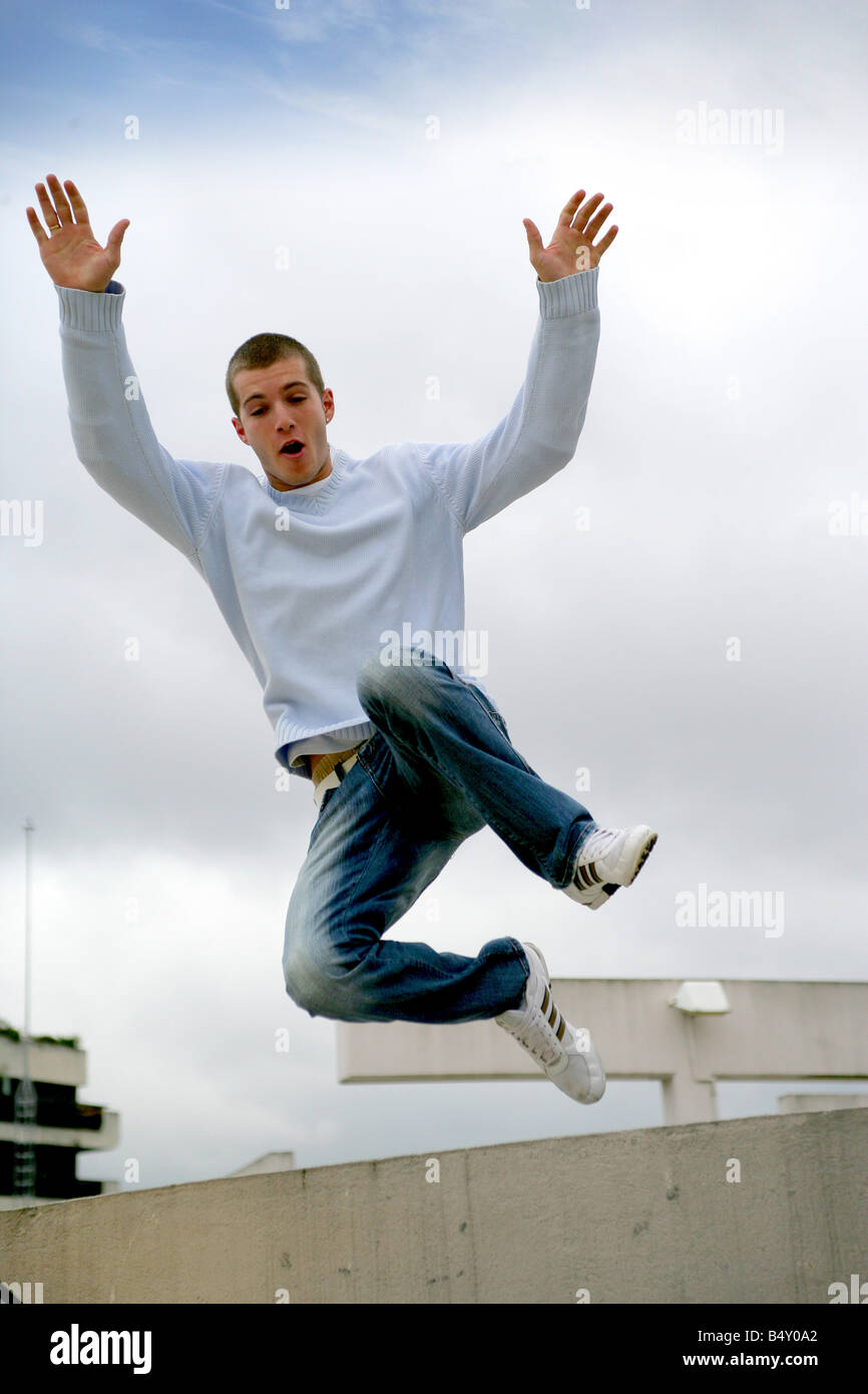 Young man jumping over a low wall Stock Photo - Alamy