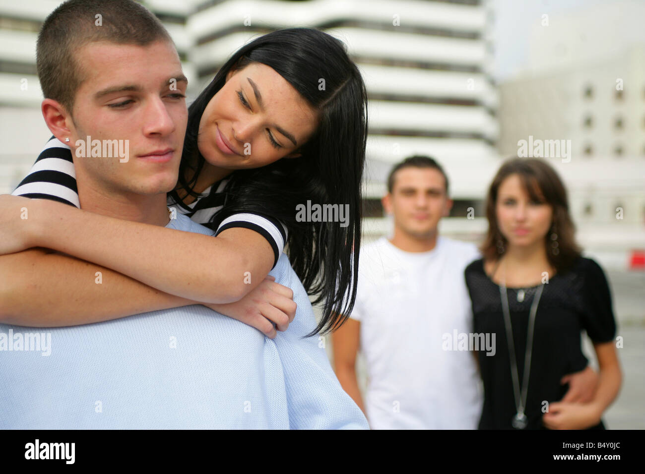 Young couple embracing with friends in background Stock Photo - Alamy