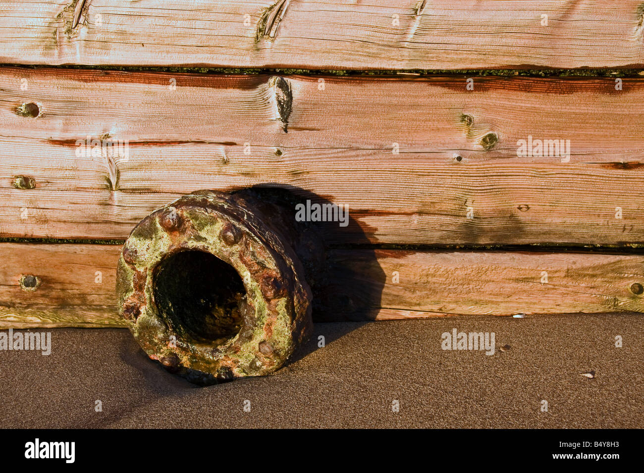 Abstract photograph of a waste pipe coming out of a wooden breakwater ...