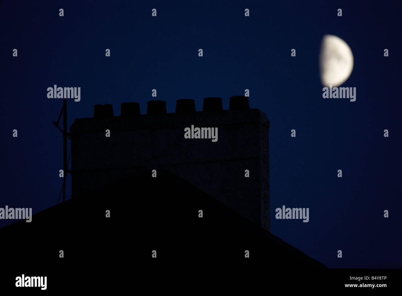 partial half moon rising over victorian chimney pot stack at night ...