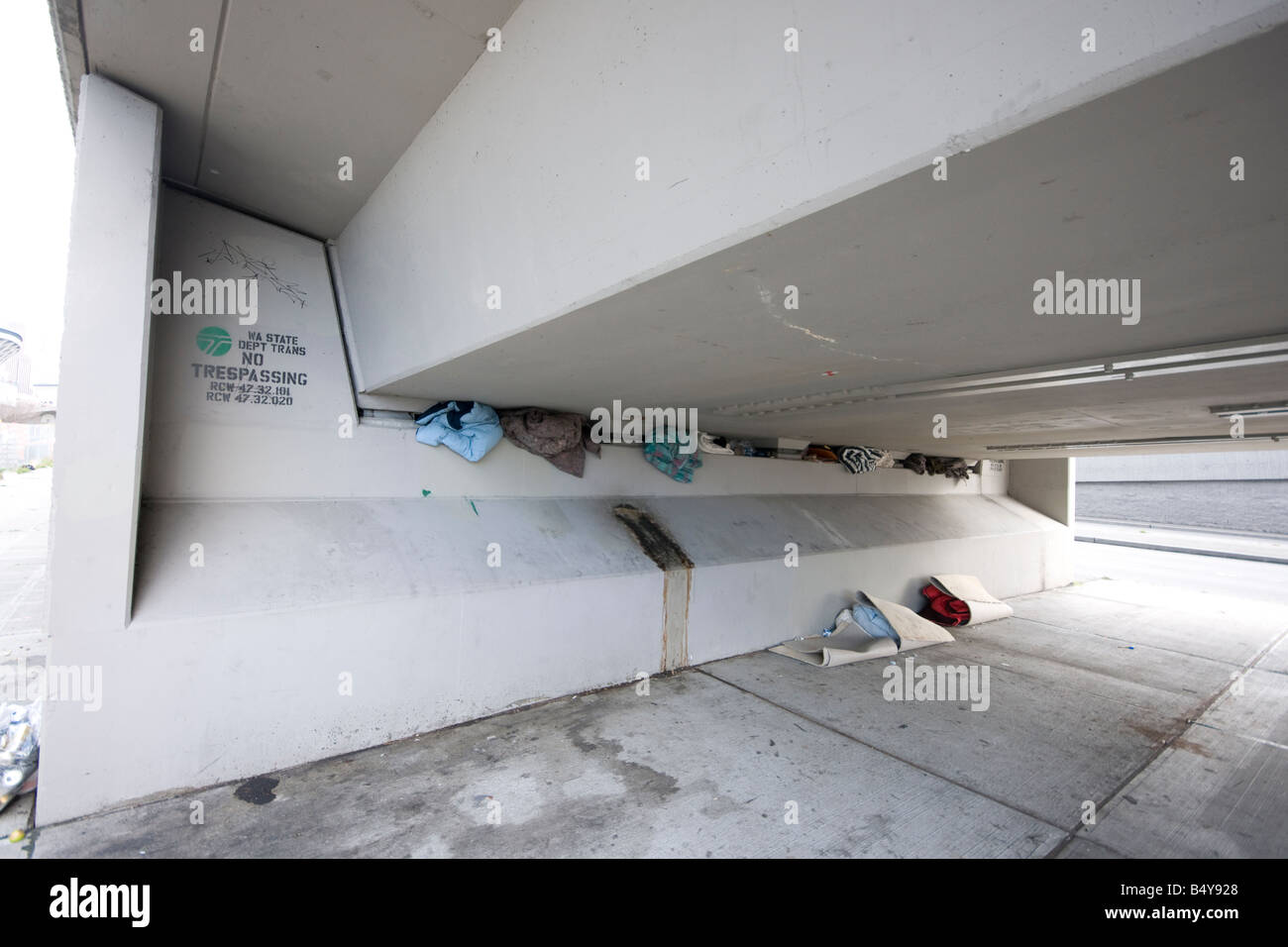 The bedding of homeless people jammed into spaces under a road bridge ...