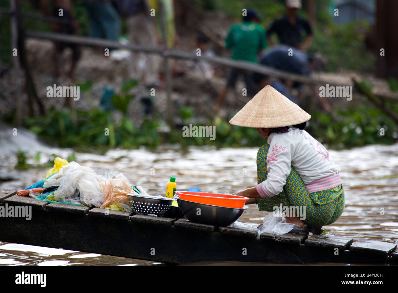 A woman washing vegetable and fish ready for cooking by the river Stock ...