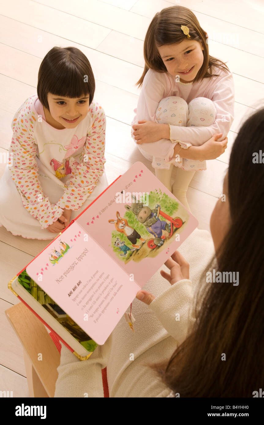 woman reading a book and two little girls Stock Photo - Alamy