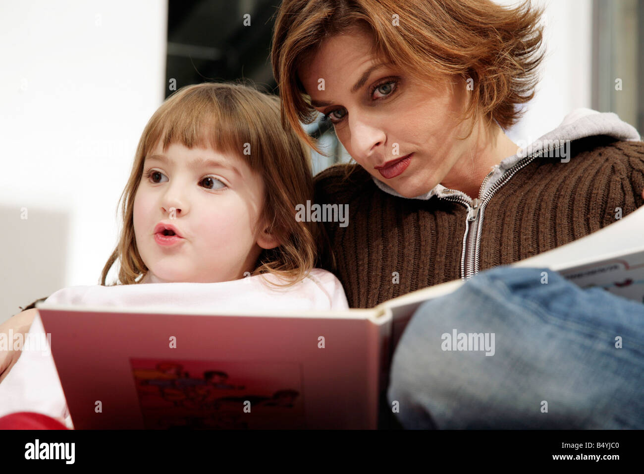 woman and little girl reading a book Stock Photo - Alamy