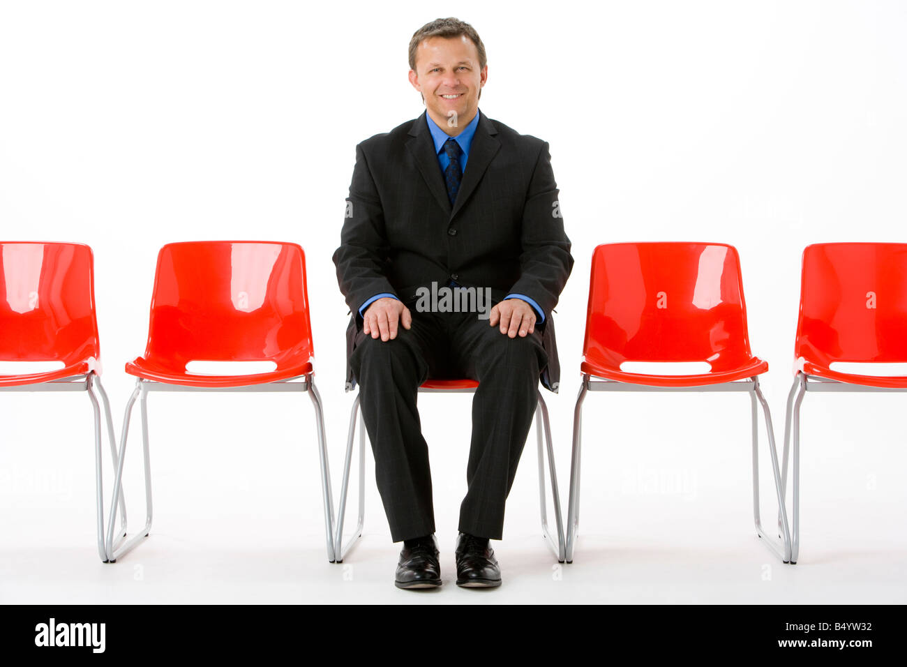 Businessman Sitting In Row Of Empty Chairs Stock Photo - Alamy