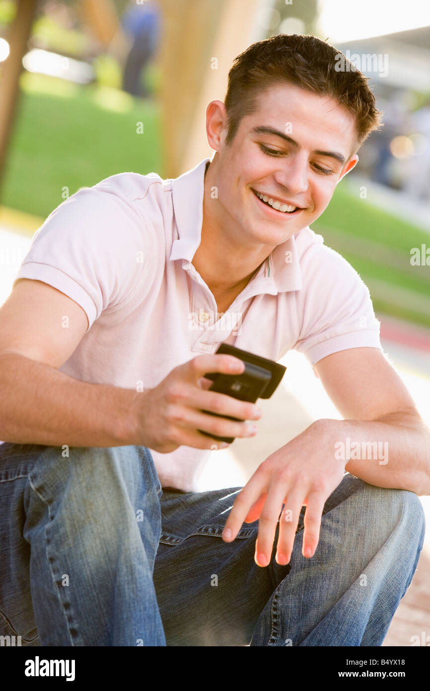 Teenage Boy Sitting Outdoors Using Mobile Phone Stock Photo - Alamy