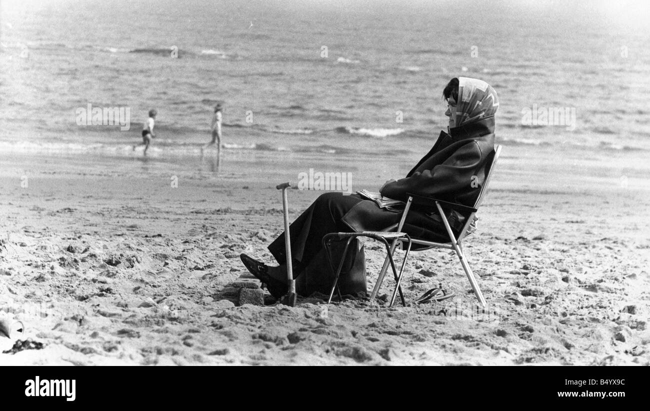 A typical British summer holiday scene a woman wrapped up in warm ...