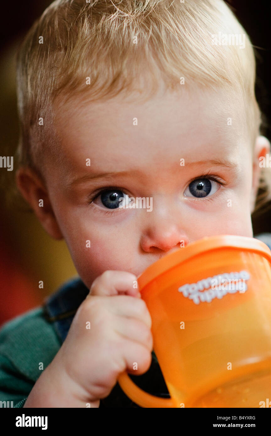 Portrait of a toddler drinking from an orange plastic beaker Stock ...