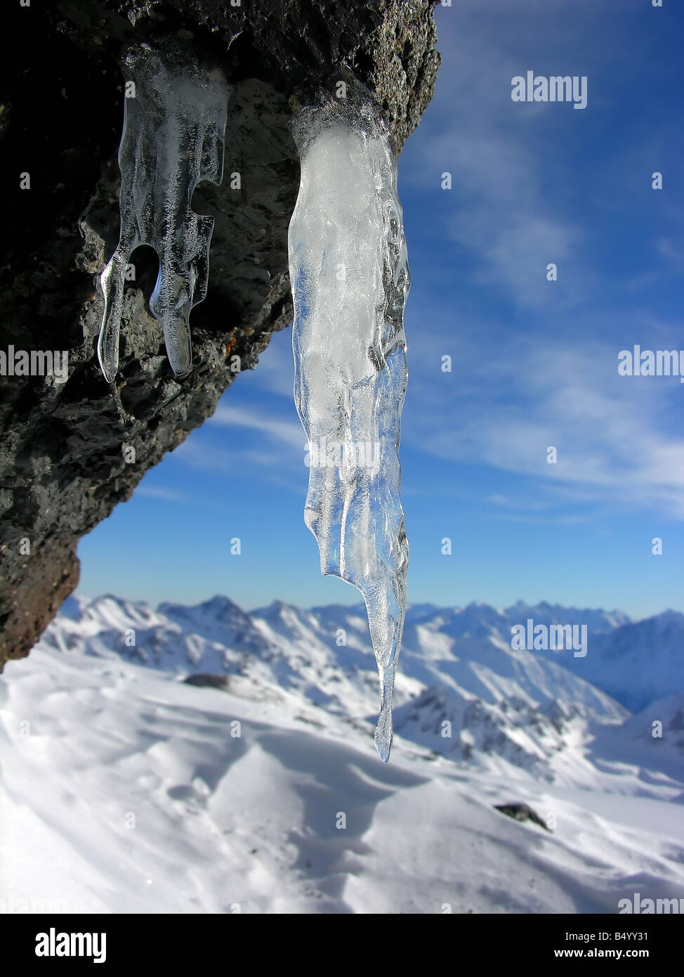 Icicle on a rock among snow covered mountains Stock Photo - Alamy