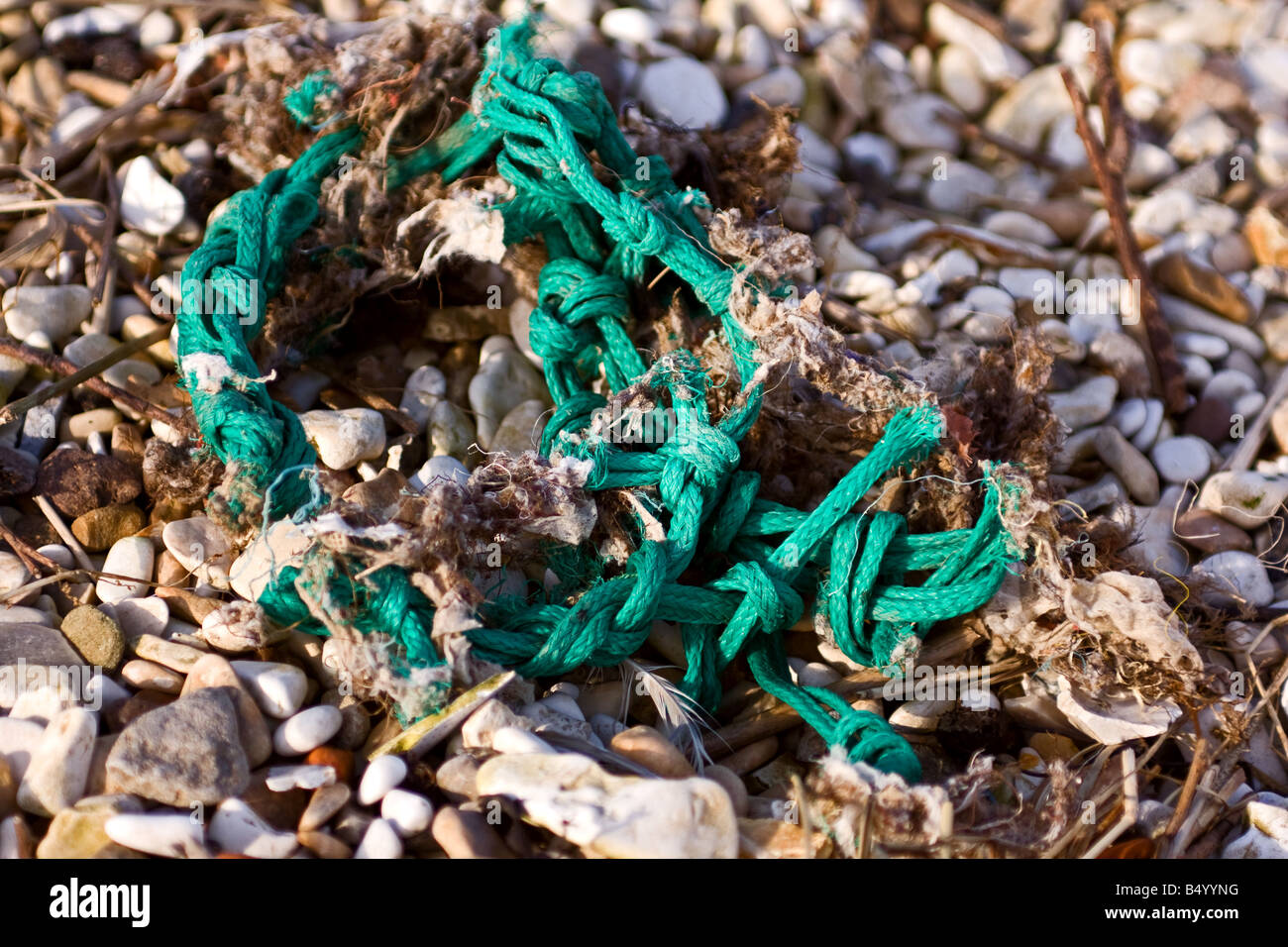Photograph of some tangled green rope on a pebble beach Stock Photo - Alamy