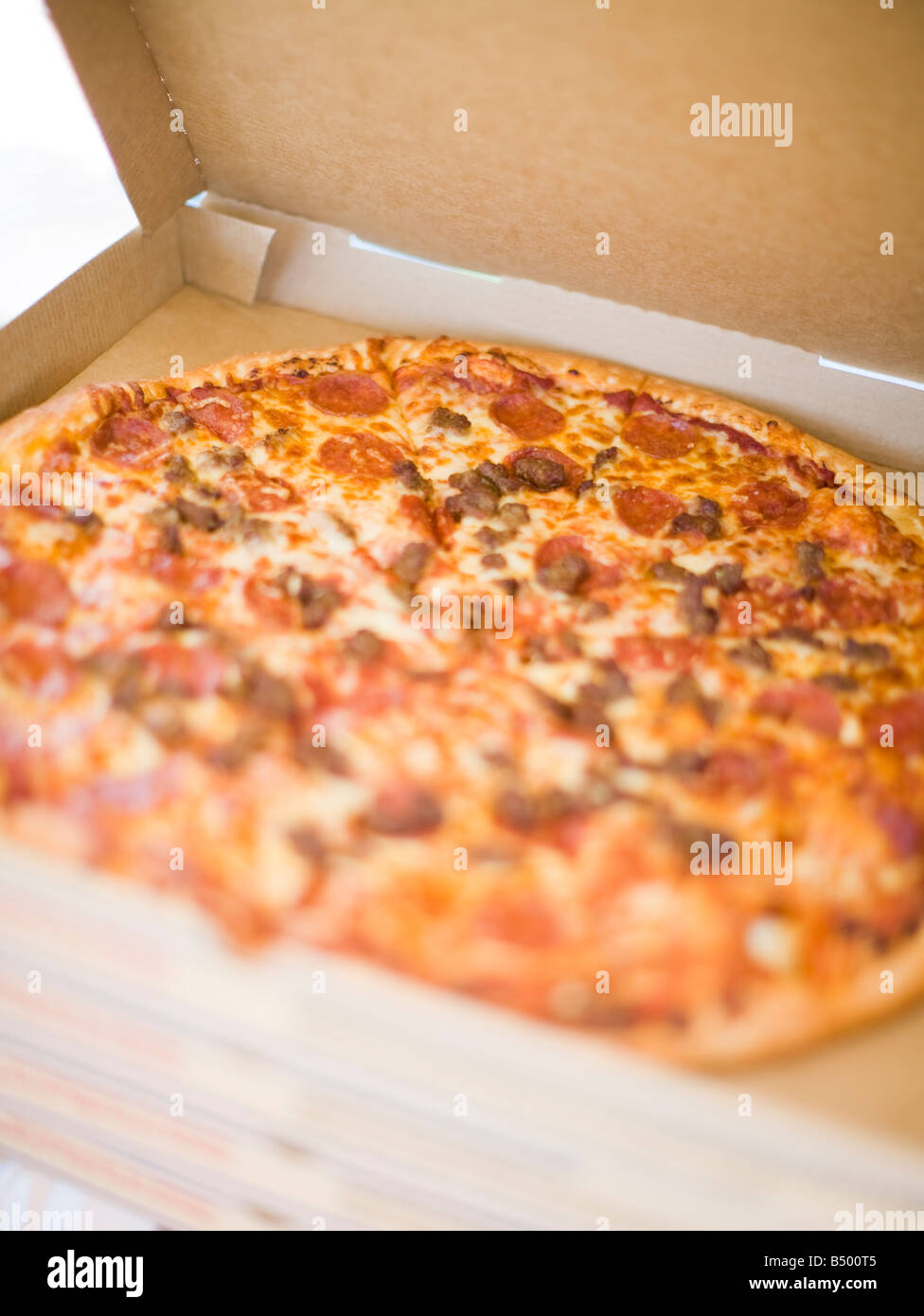 full pizza being shown with the lid open on a stock of four pizza boxes ...