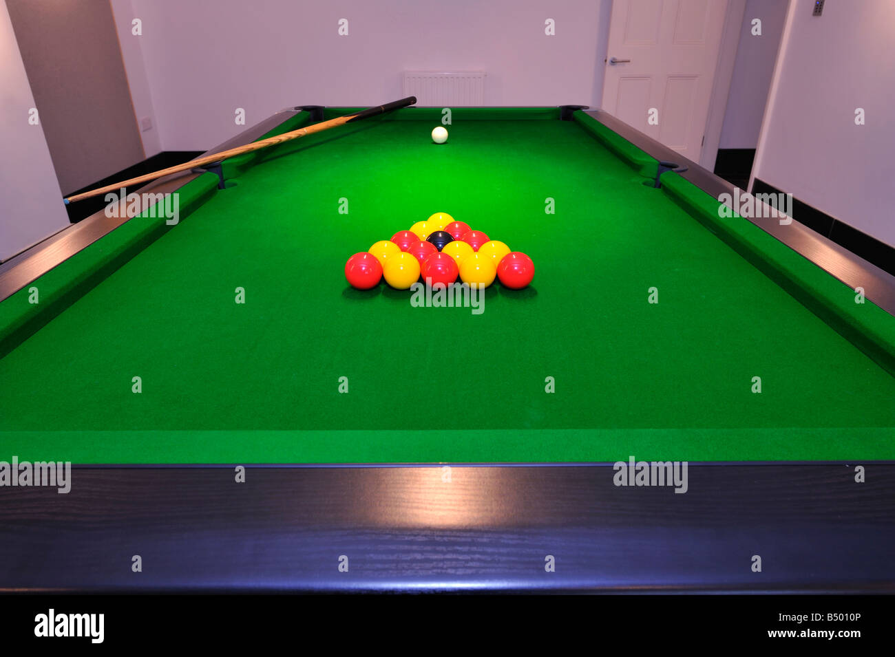 Low angle shot of along a pool table with framed balls, cue, white ball ...