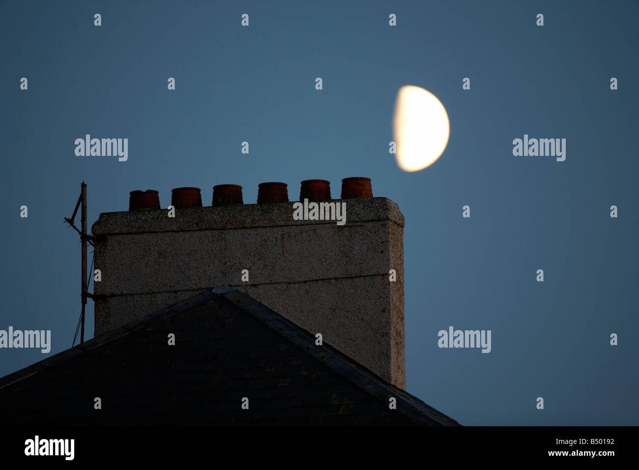 partial half moon rising over victorian chimney pot stack at night ...