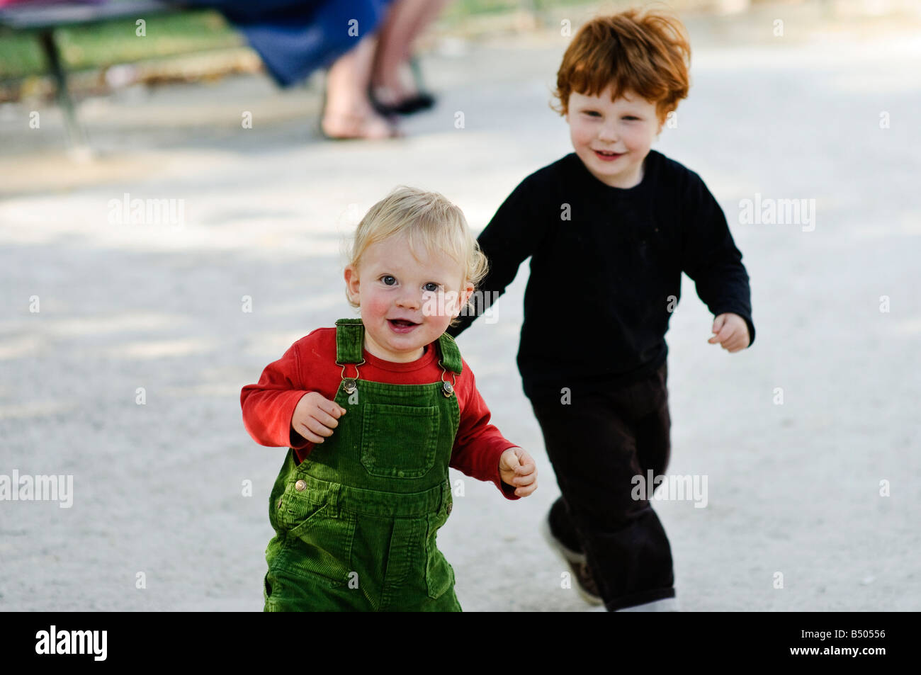 Two boys playing chase in a park Stock Photo - Alamy