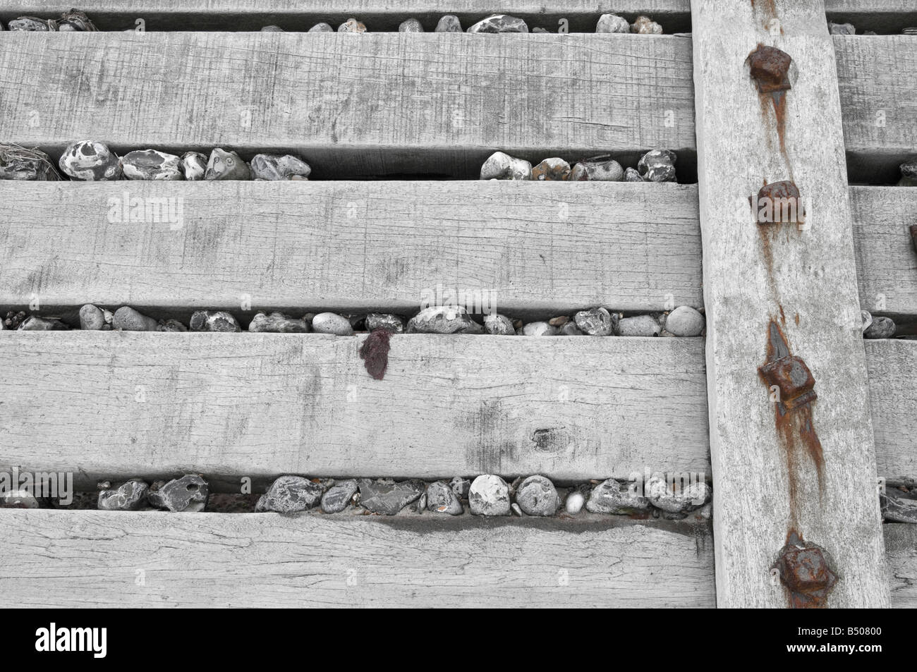 Wooden sea defences with pebbles lodged between planks Stock Photo - Alamy