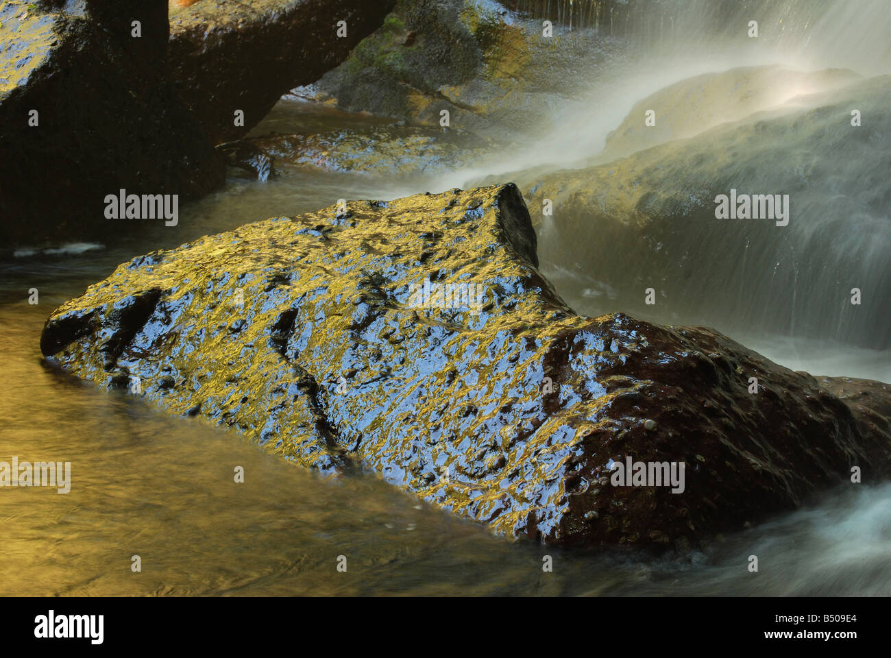 Golden autumn light reflected at the foot of a waterfall in Glen ...