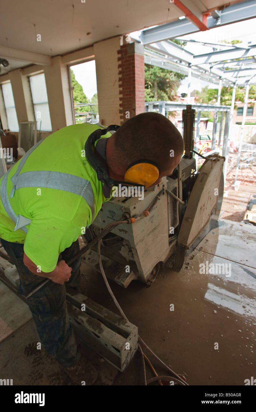 Building worker operating machinery, cutting through concrete floor ...
