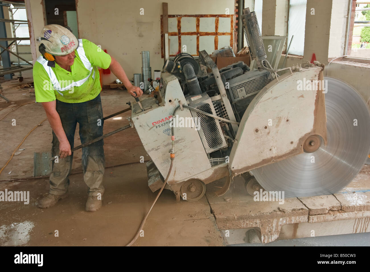 Building worker operating machinery, cutting through concrete floor ...