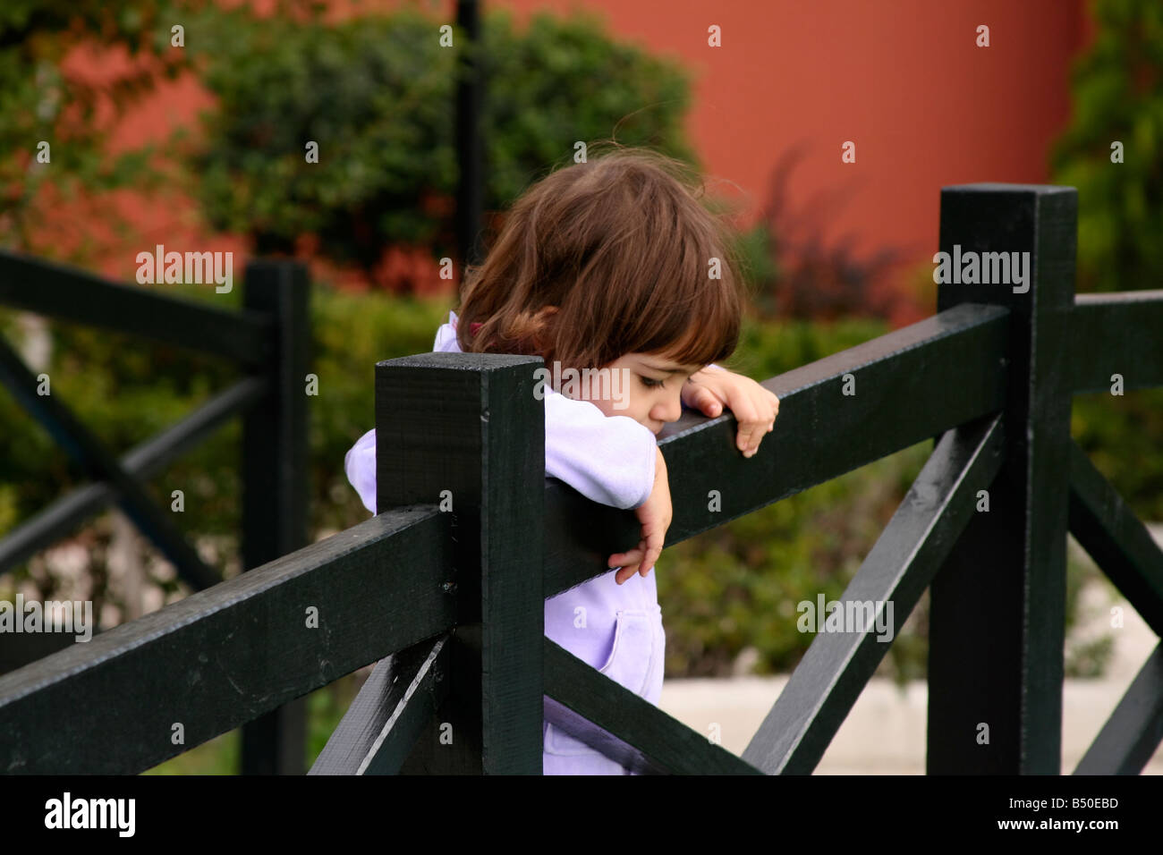 Little girl looking down over the wooden bridge barrier Stock Photo - Alamy