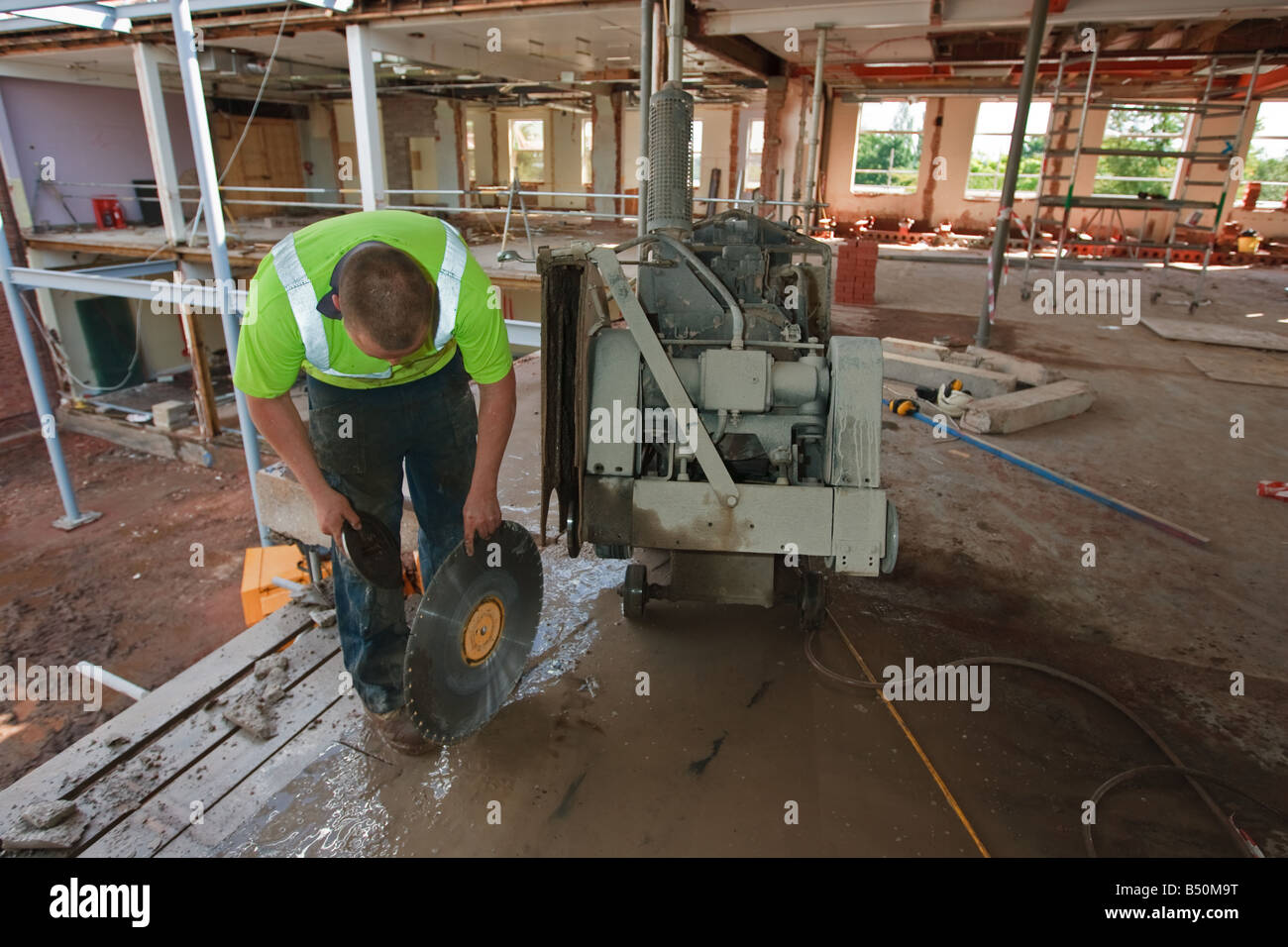 Building worker operating machinery, cutting through concrete floor ...