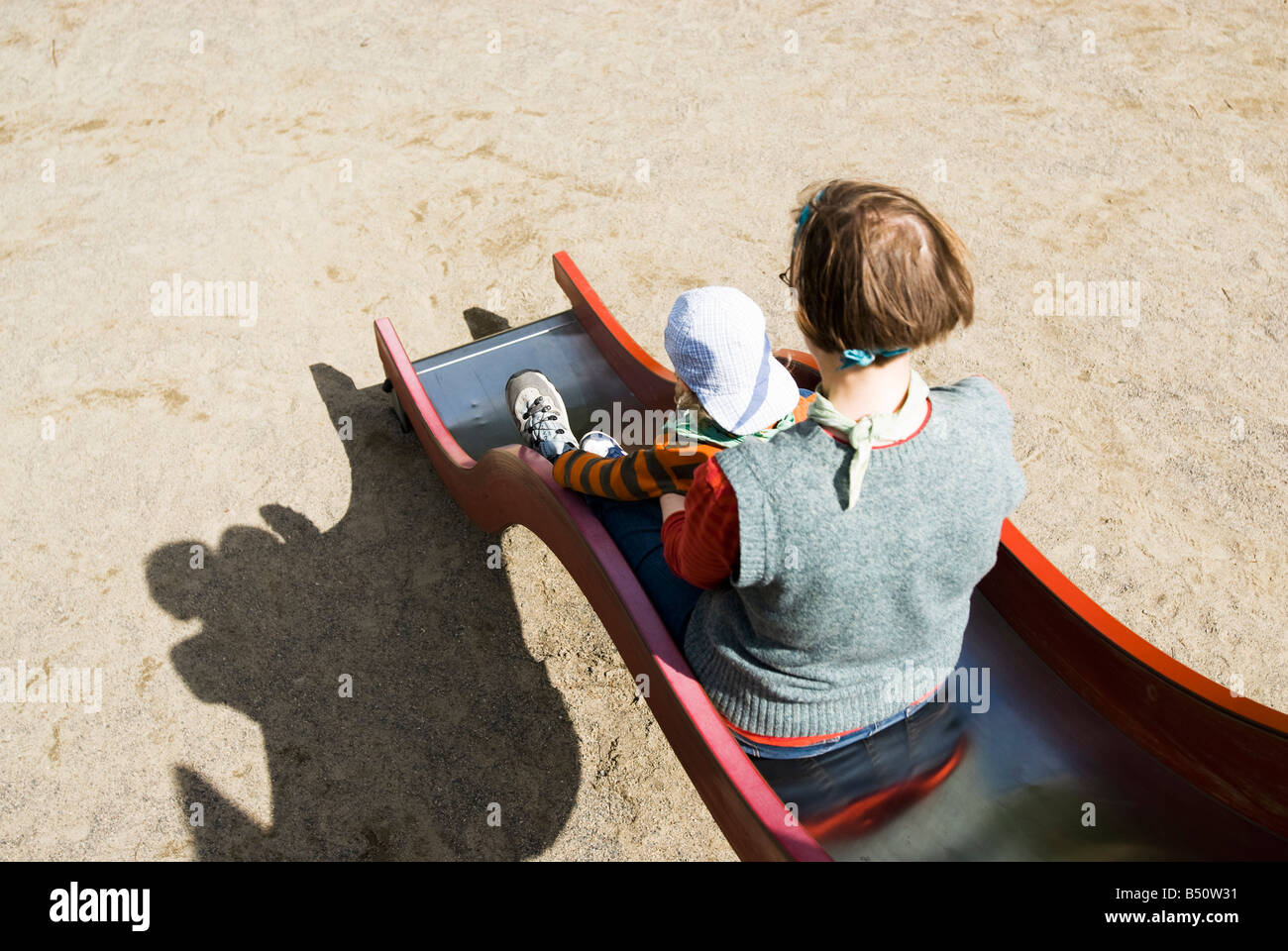 High angle view of a mid adult woman sliding on a slide with her son ...
