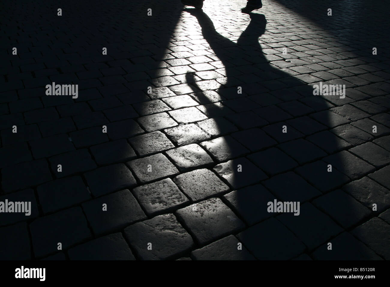 person shadow walking on cobbled street in morning sun Stock Photo - Alamy