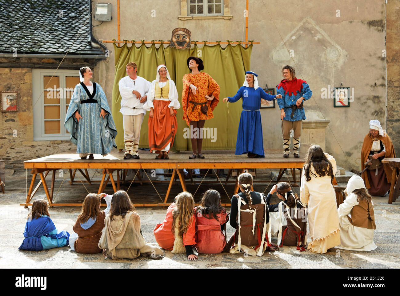 Children dressend in Medieval costumes watch a French play in Estaing ...