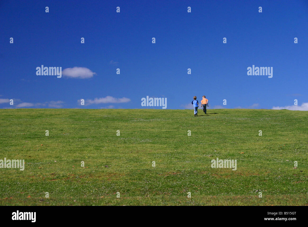 Two children running in open grassy field Stock Photo - Alamy