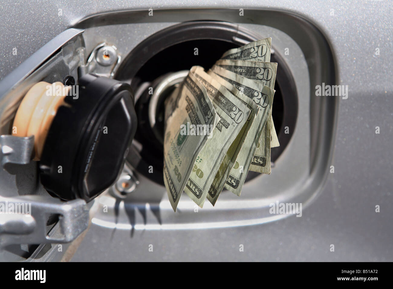 Money down the fuel tank Stock Photo - Alamy