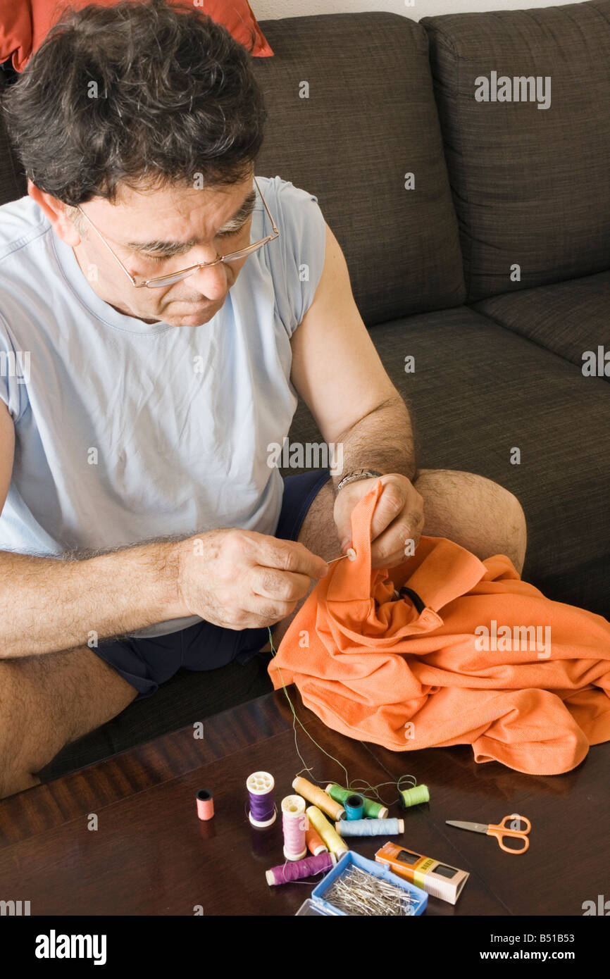 Man sewing button on shirt Stock Photo - Alamy