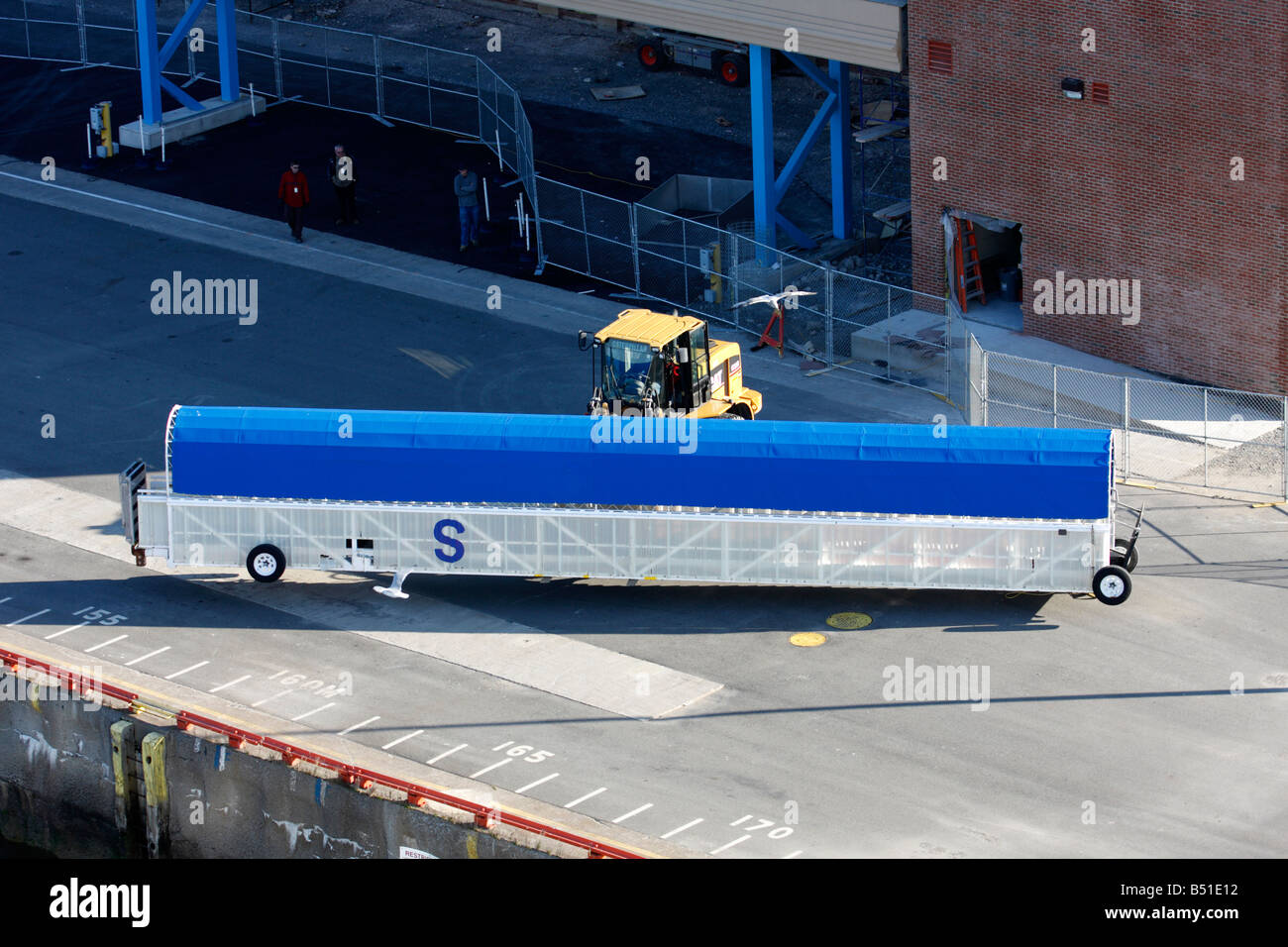 A forklift preparing to lift a cruise ship disembarkation passageway in ...