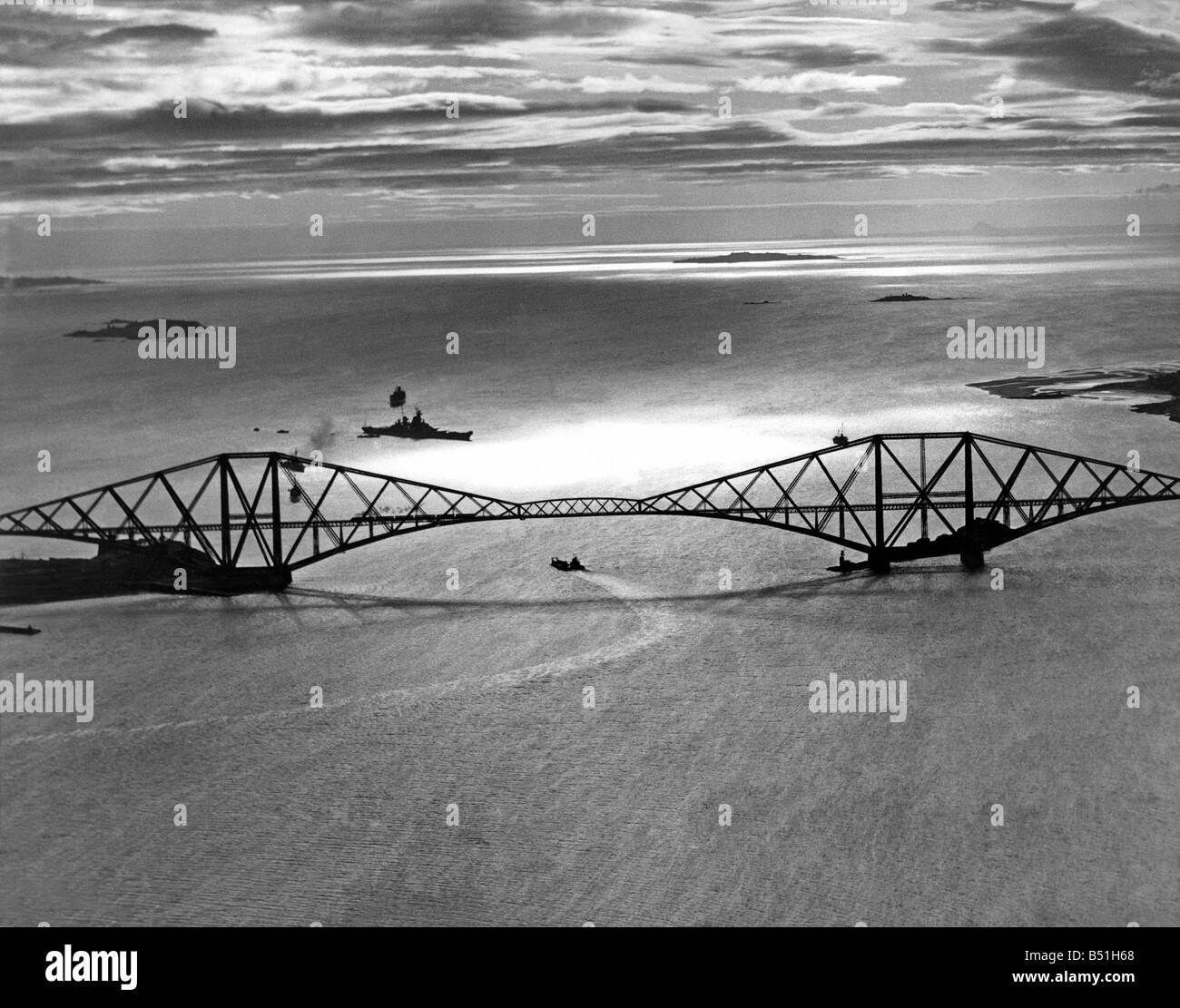 A Royal Navy battleships passes underneath the Forth bridge s it ...