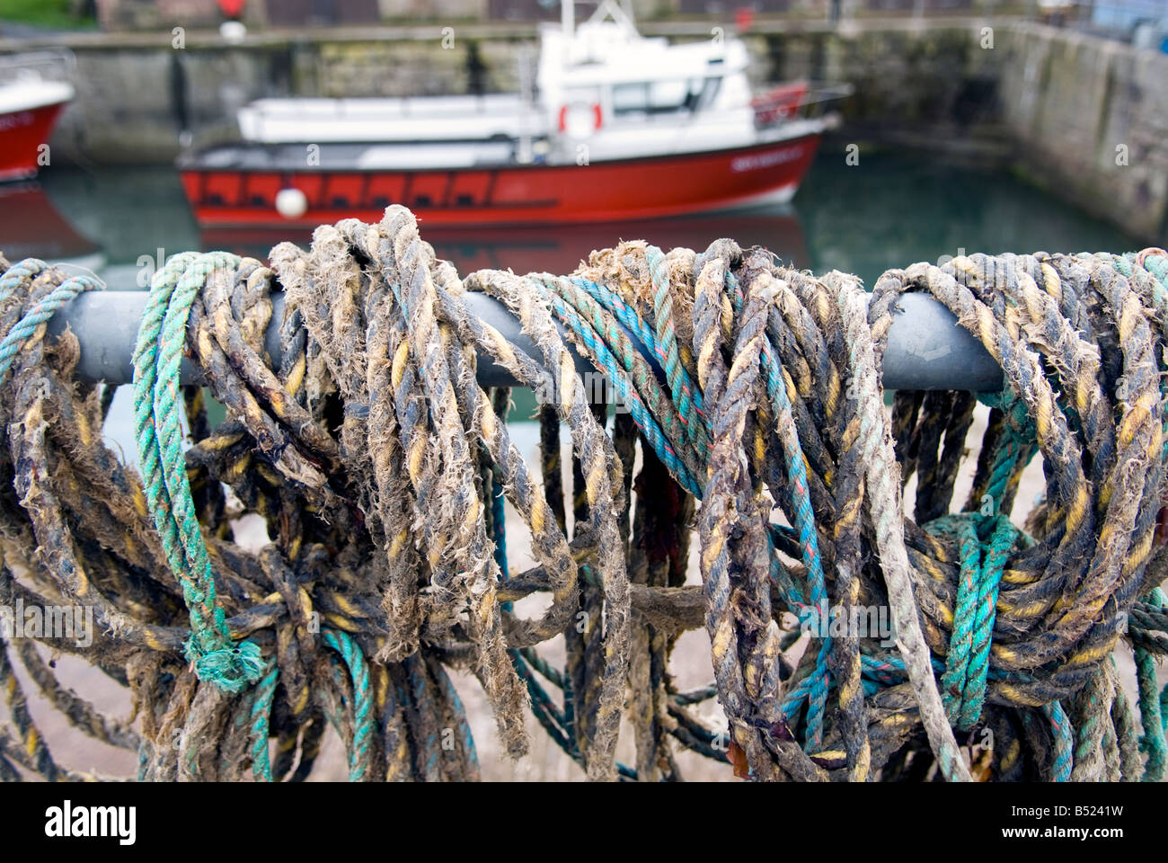Fishing boat ropes tied around harbour railings Stock Photo - Alamy