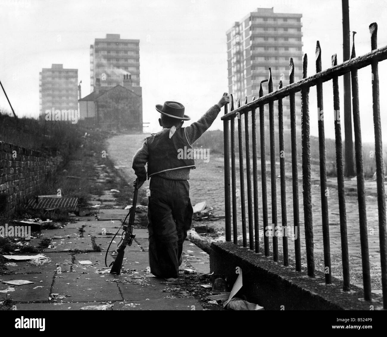 Boy dressed as cowboy staring out at newly built tower blocks in ...
