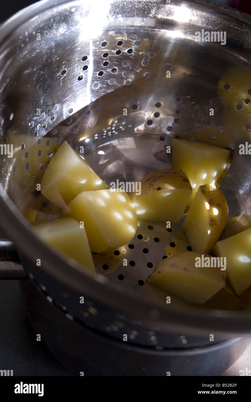 Boiled new potatoes draining in a colander Stock Photo - Alamy