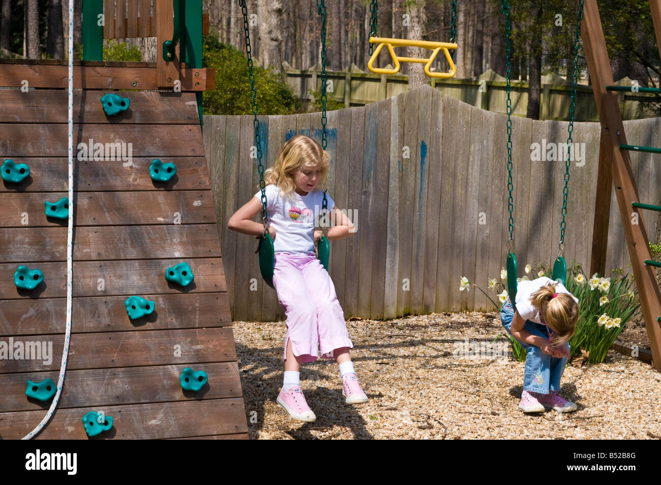 Two sisters play on back yard swings Stock Photo - Alamy