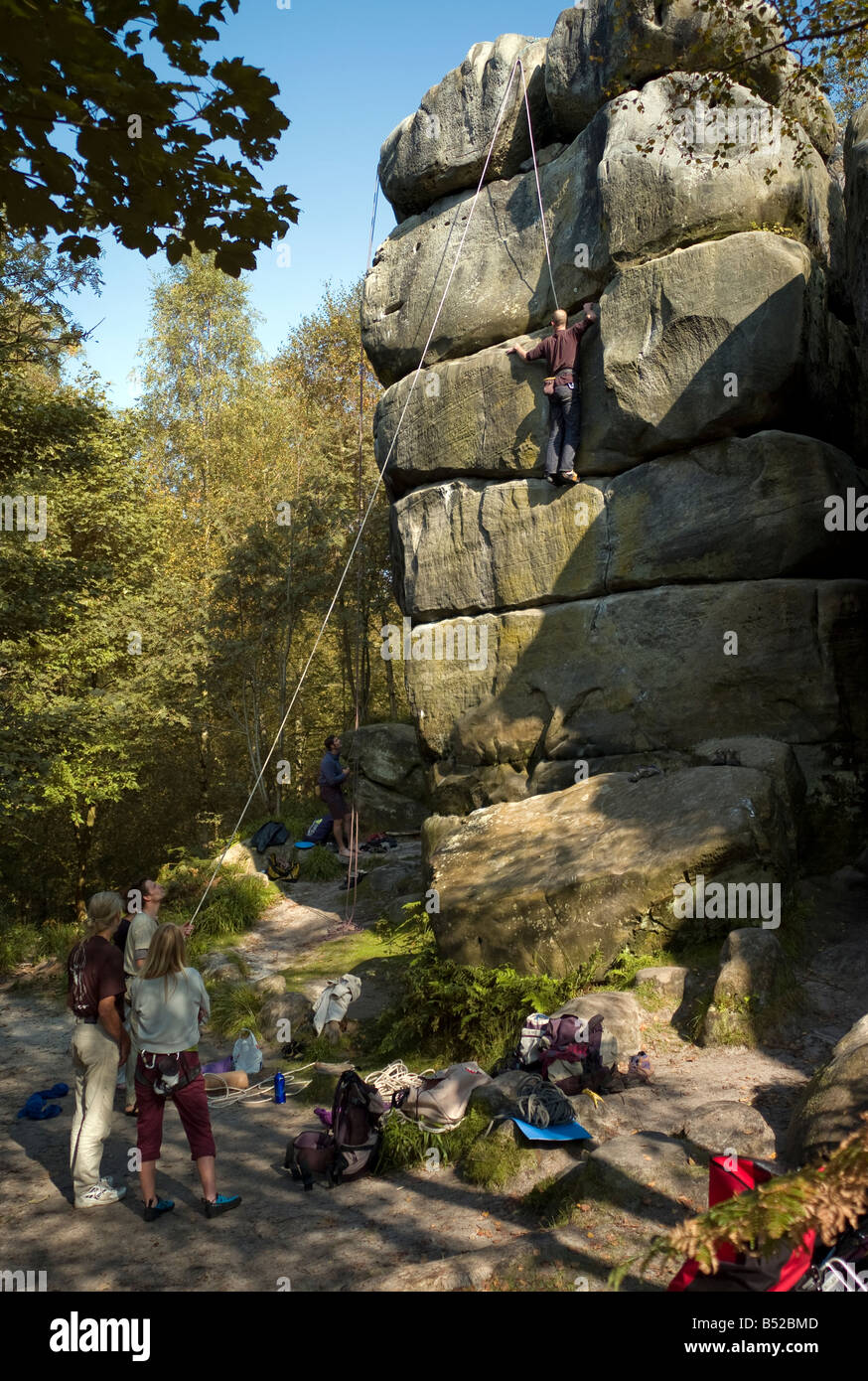 Group of people enjoying outdoor pursuits, climbing on sandstone crag ...
