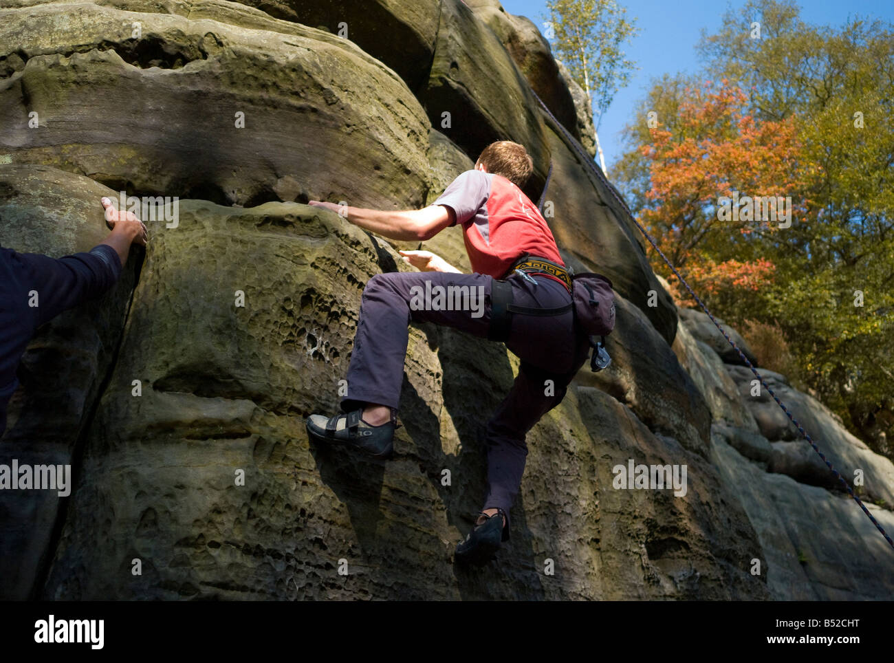 Young man climbing up sandstone crag, Harrisons Rocks, near Groombridge ...