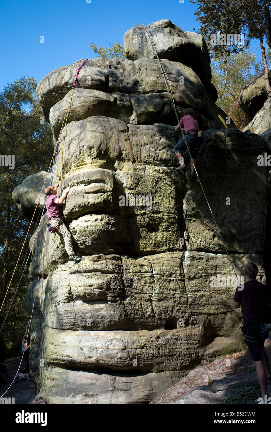 Two climbers reaching the top of sandstone rock, Harrisons Rocks, near ...