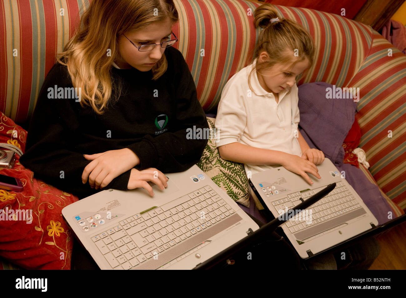 two welsh girls, sisters school children using laptop computers to send ...