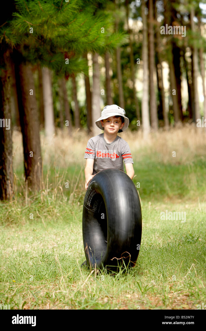 child 8 playing with large black inner tube from car as toy in summer ...