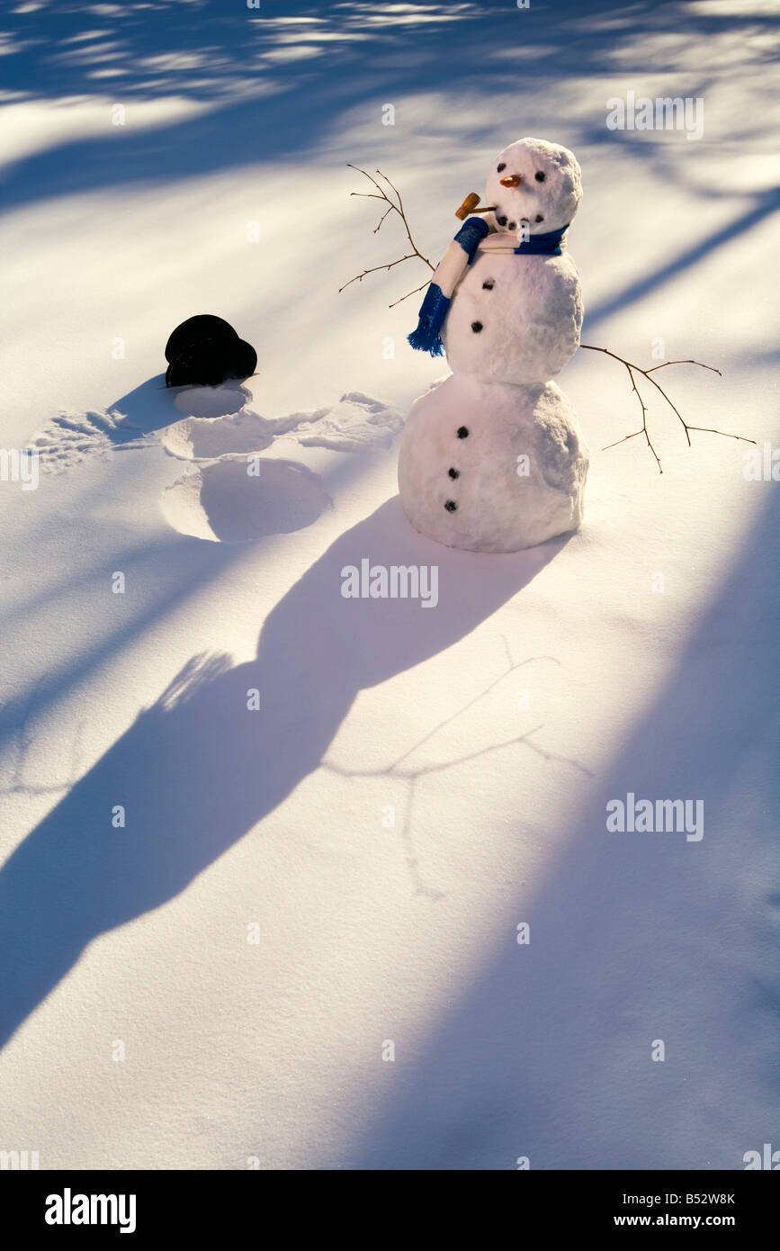 Snowman in forest making snow angel imprint in snow in late afternoon ...
