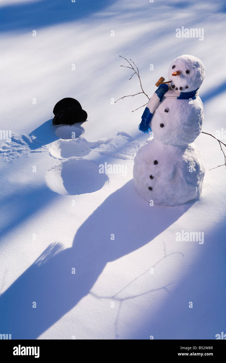 Snowman in forest making snow angel imprint in snow in late afternoon ...
