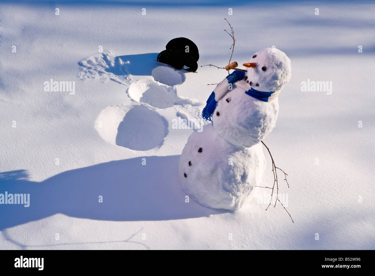 Snowman in forest making snow angel imprint in snow in late afternoon ...
