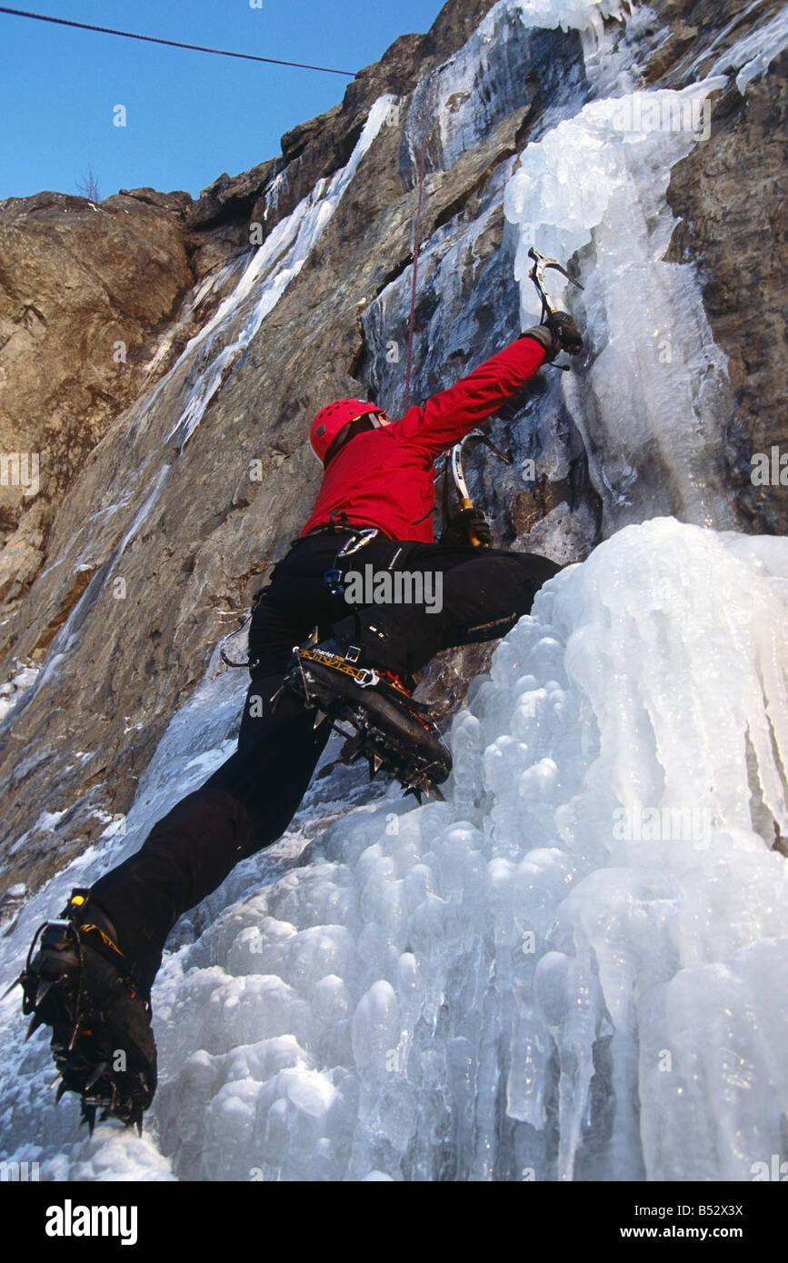 Male ice climber using ice picks to climb frozen waterfall on Turnagain ...