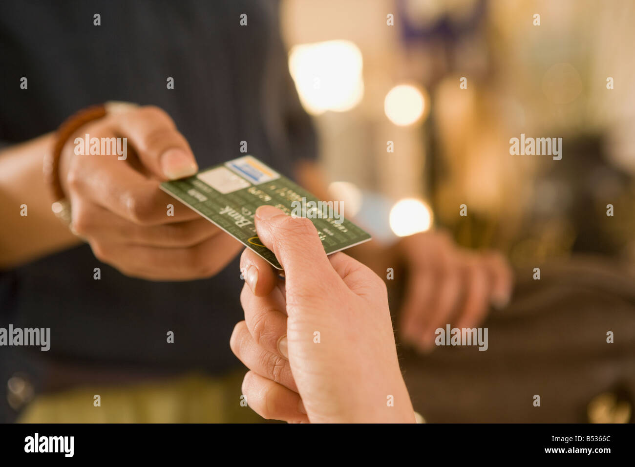 Mixed race woman handing credit card to cashier Stock Photo - Alamy