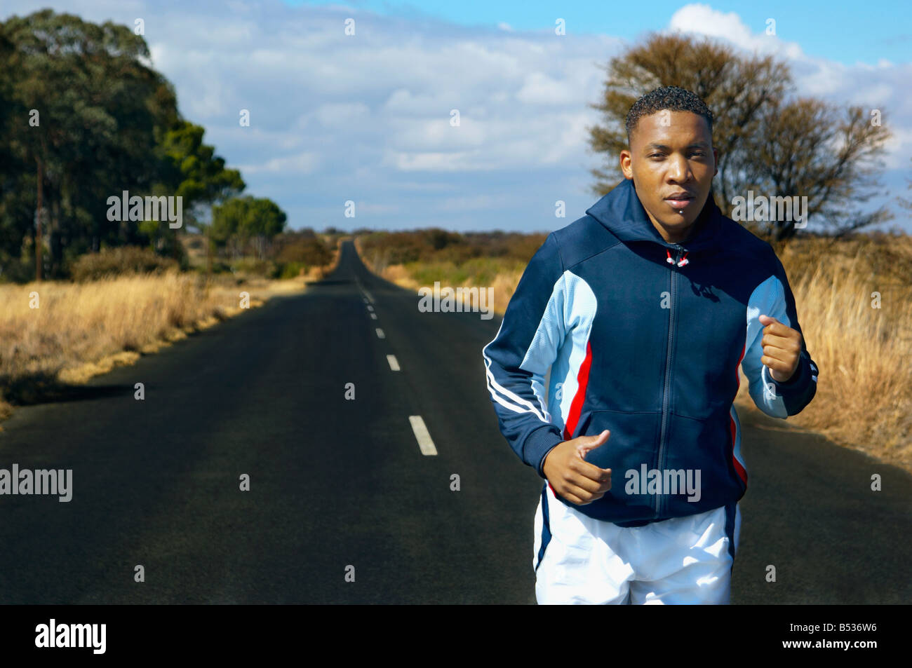 Mixed race man running on remote road Stock Photo - Alamy