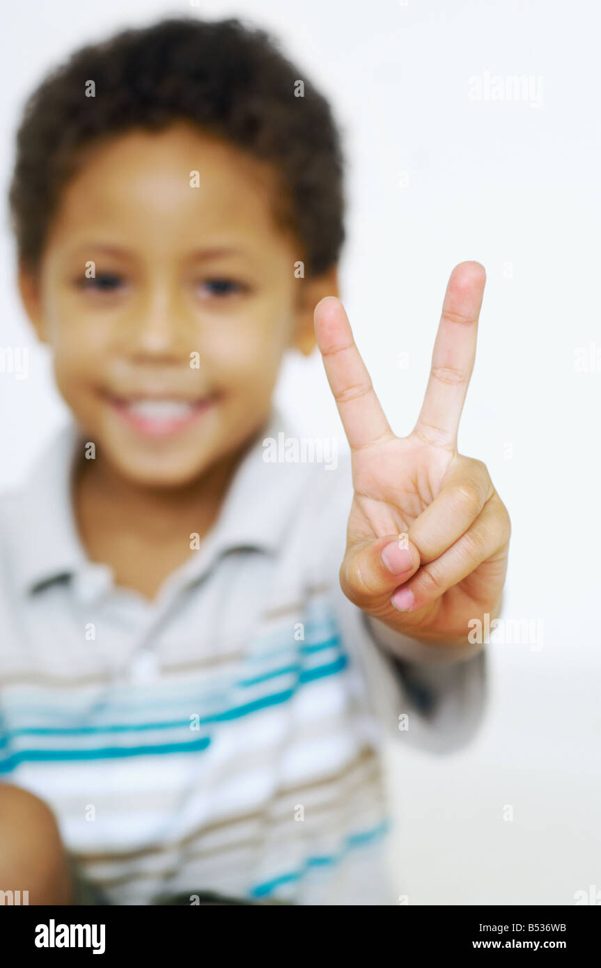 Mixed race boy gesturing the peace sign Stock Photo - Alamy