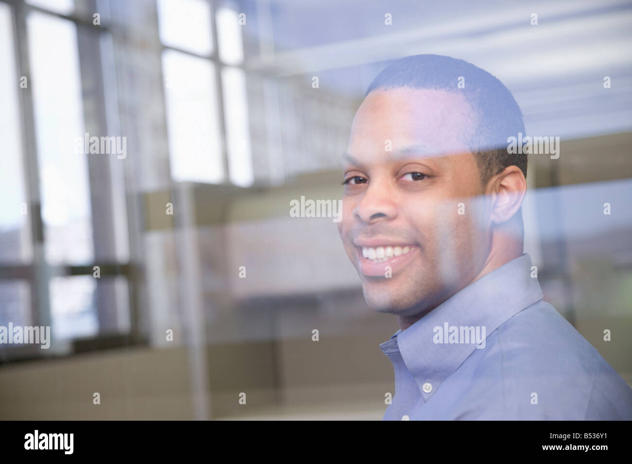 African businessman smiling through window Stock Photo - Alamy