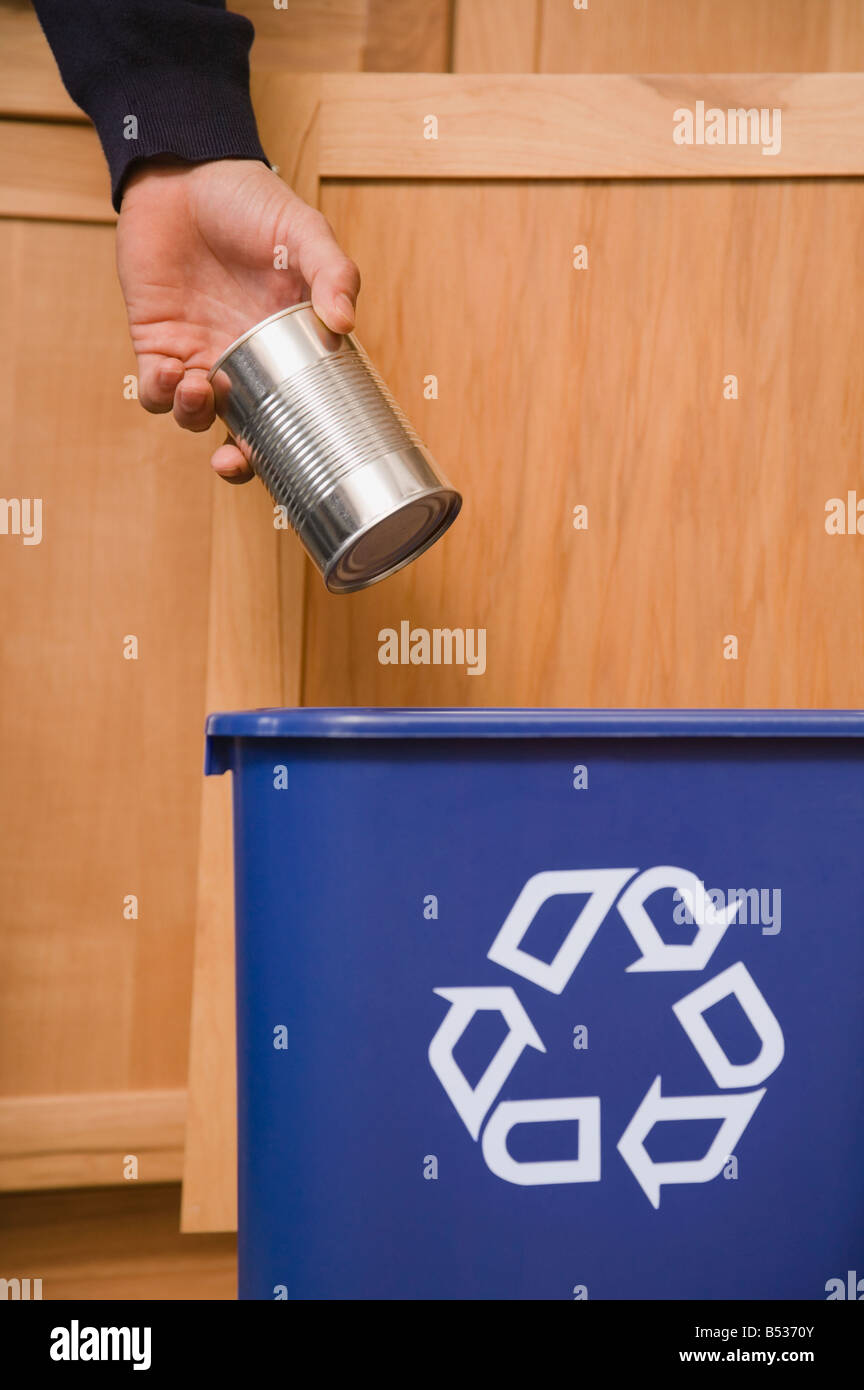 Hispanic man placing tin can in recycling bin Stock Photo - Alamy